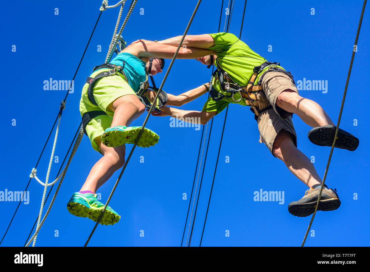 Two young people doing partner exercise in high ropes course Stock ...