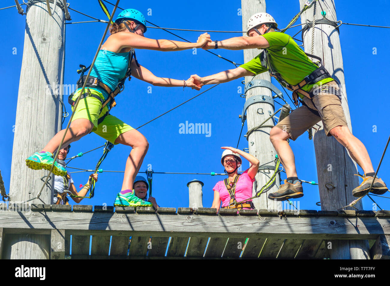 Two young people doing partner exercise in high ropes course Stock ...