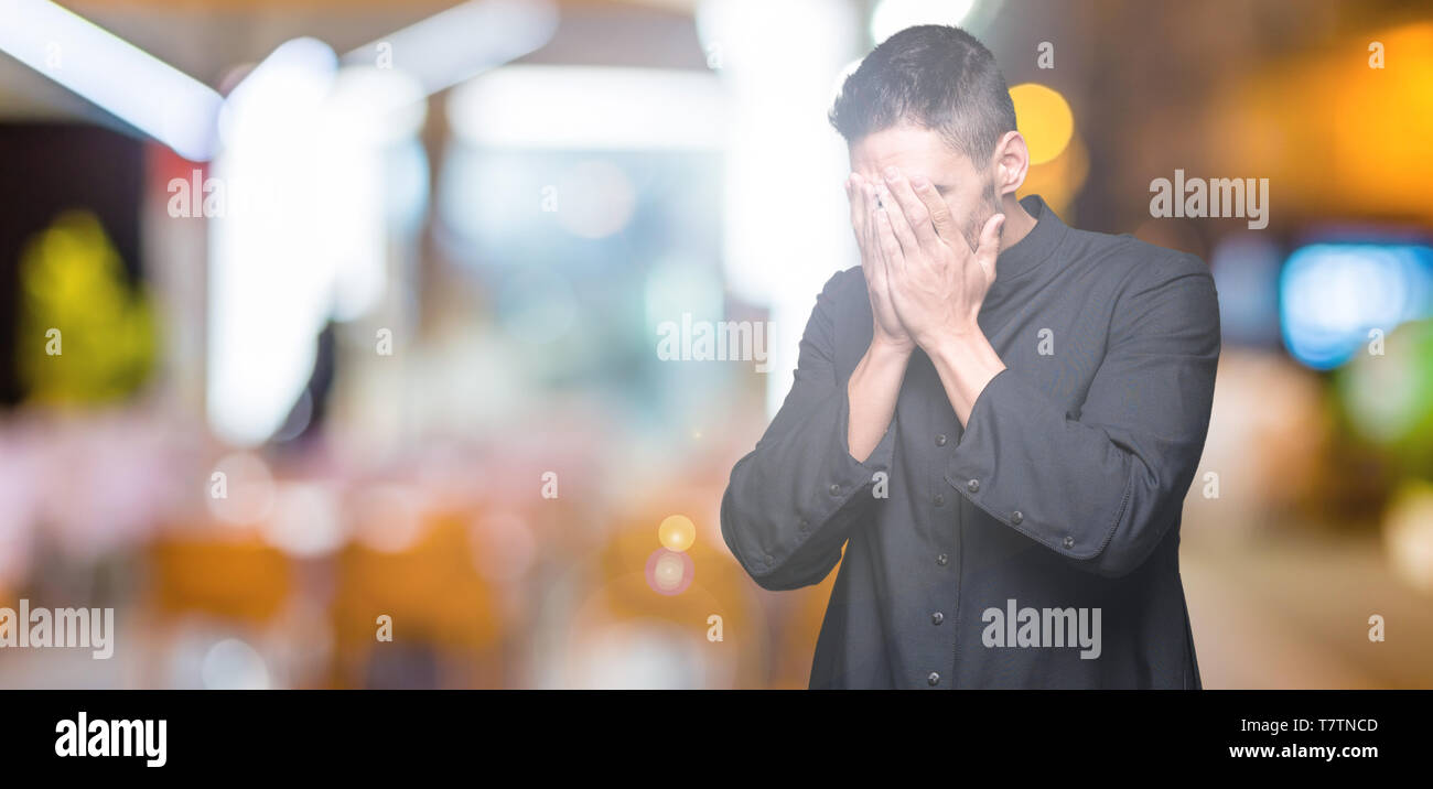 Young Christian priest over isolated background with sad expression ...