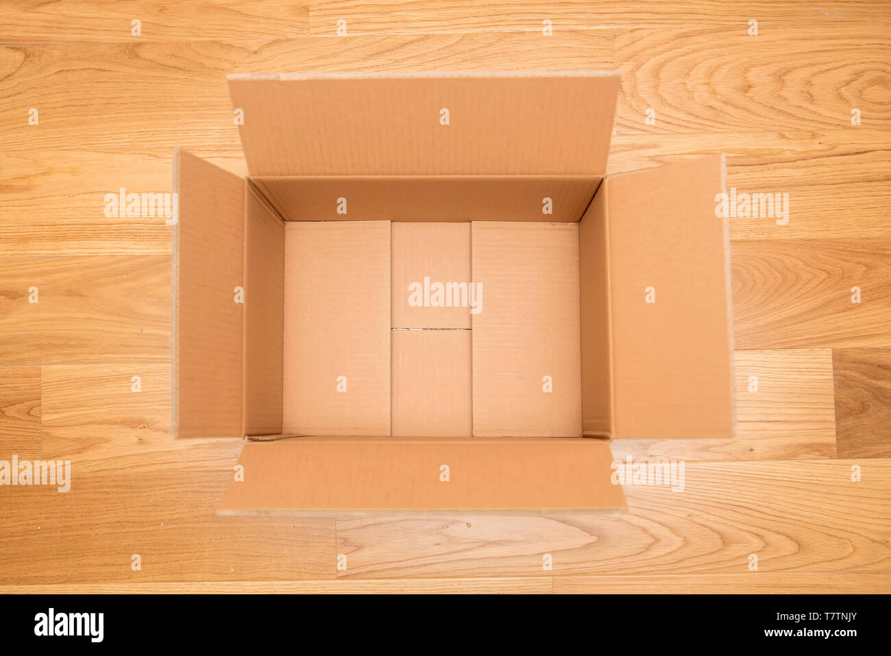 Top view at open cardboard box on the floor in empty room, ready for ...