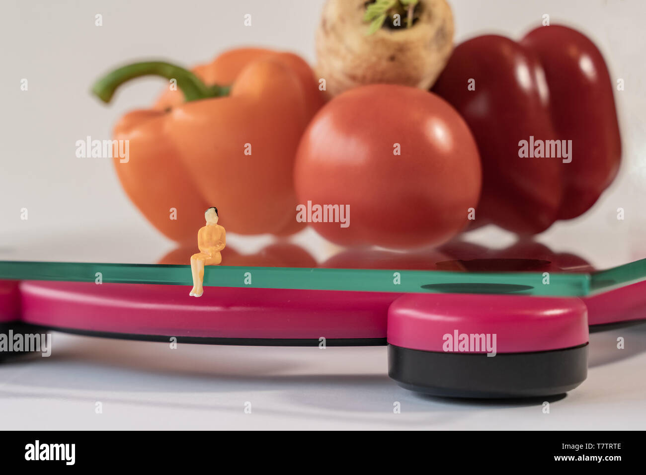 Miniature woman figure siting on the digital electronic bathroom scale ...