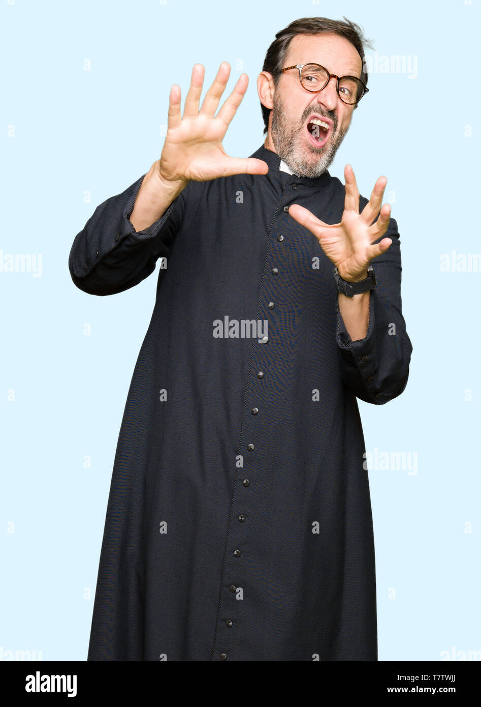 Middle age priest man wearing catholic robe afraid and terrified with ...