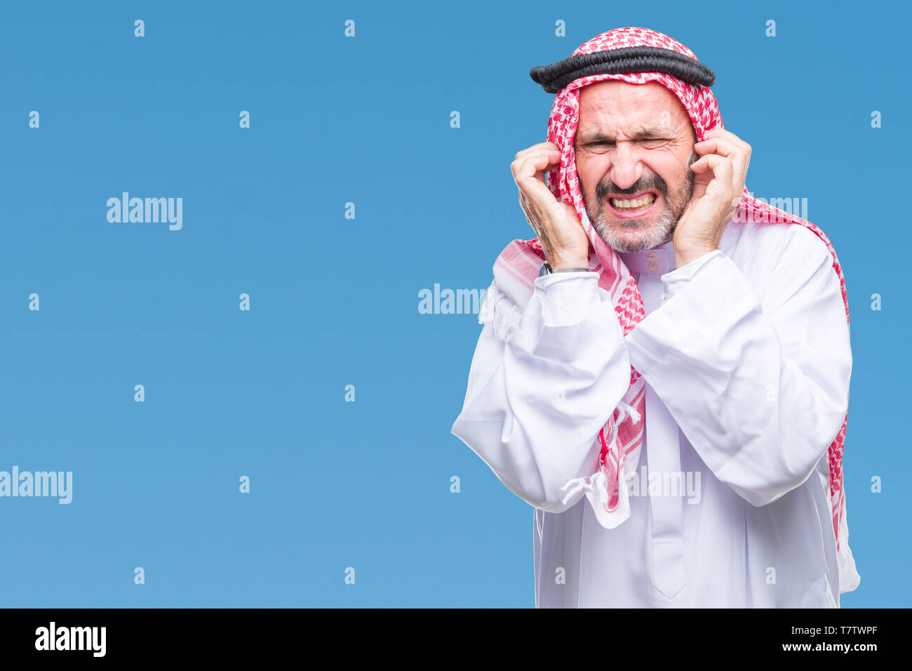 Senior arab man wearing keffiyeh over isolated background covering ears ...