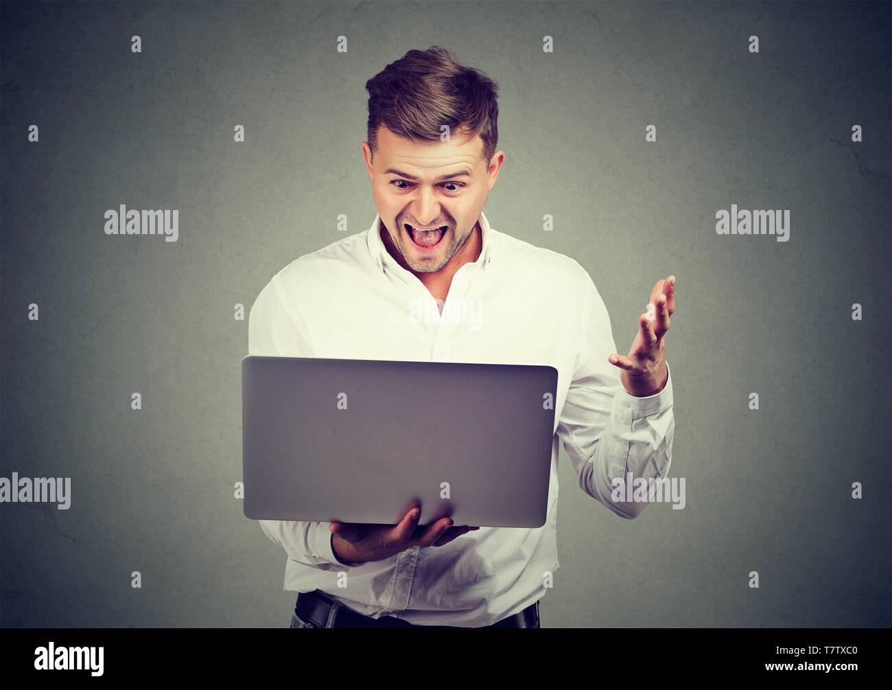 Super excited man reading great news on his laptop Stock Photo - Alamy