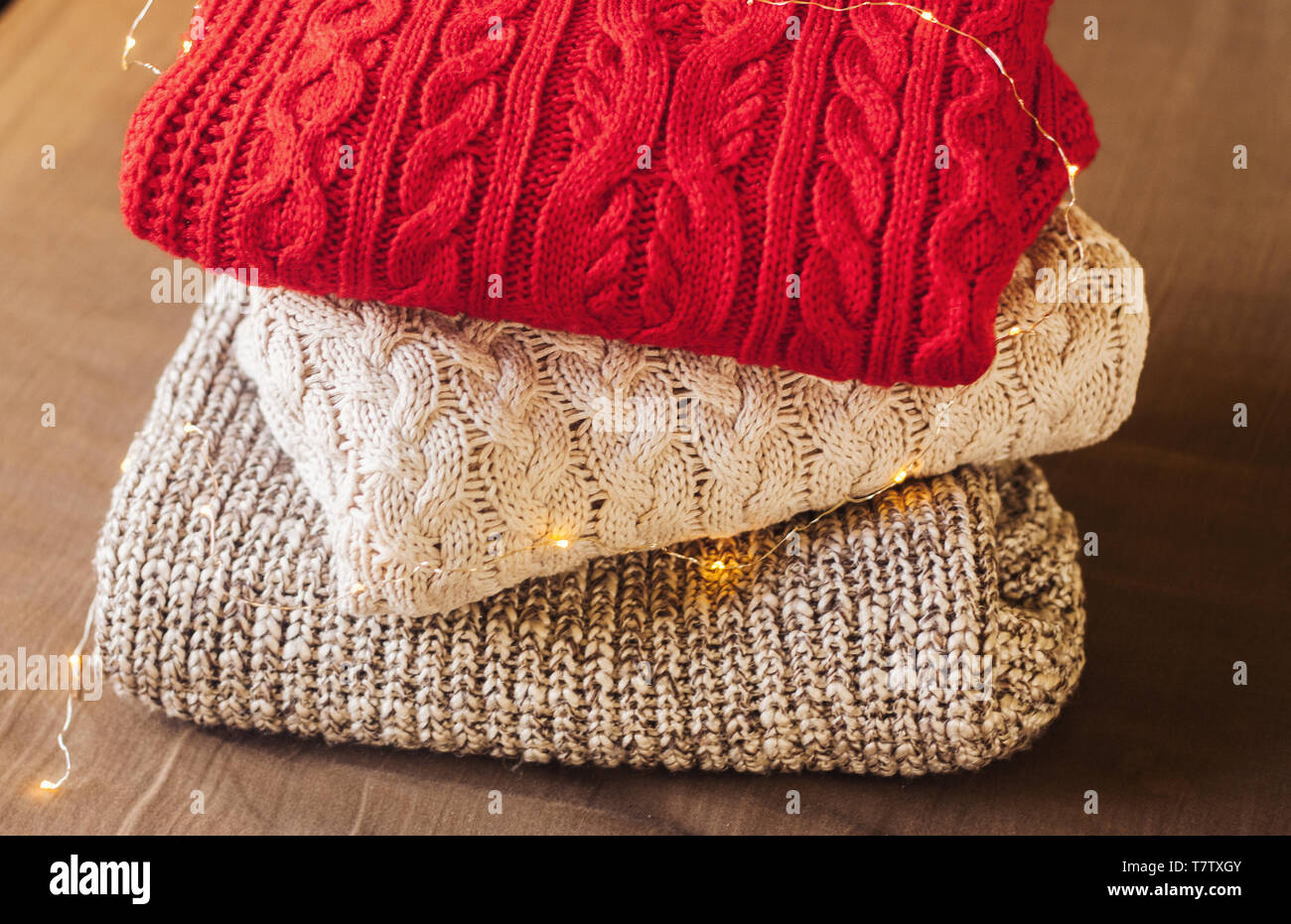A pile of knitted sweaters on the brown tissue background decorated ...