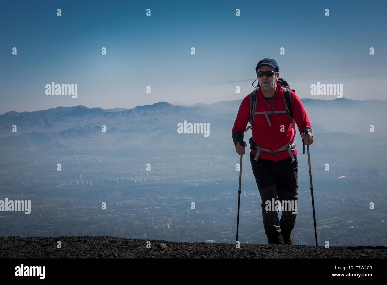 A climber in red clothes on the top of snow mountain and city in on the ...