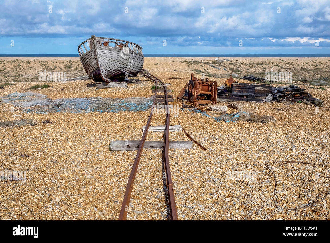 Old rusty train track on a big flat pebble beach leading to an old ...