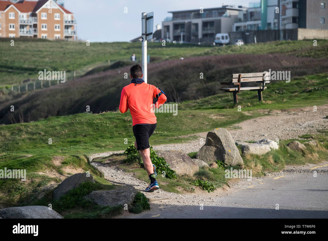 A runner jogging on a path on Towan Head in Newquay in Cornwall Stock ...