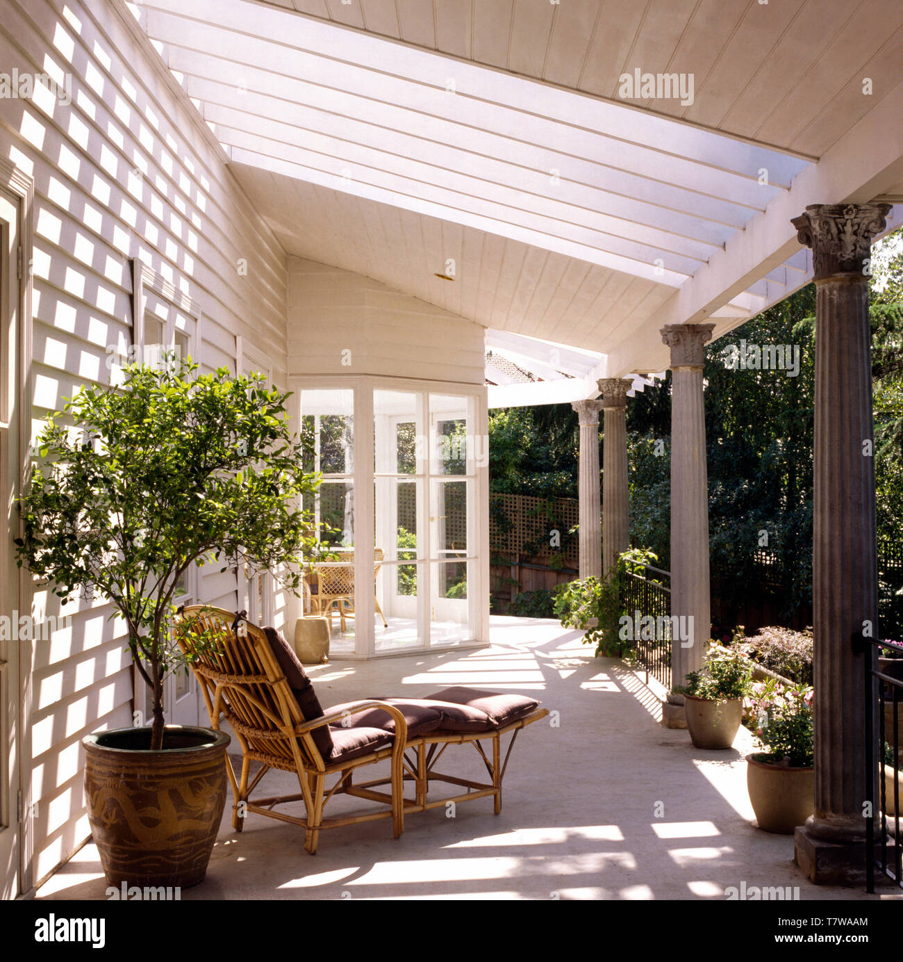 Small tree in an oriental pot beside a cane lounger on the veranda of a ...