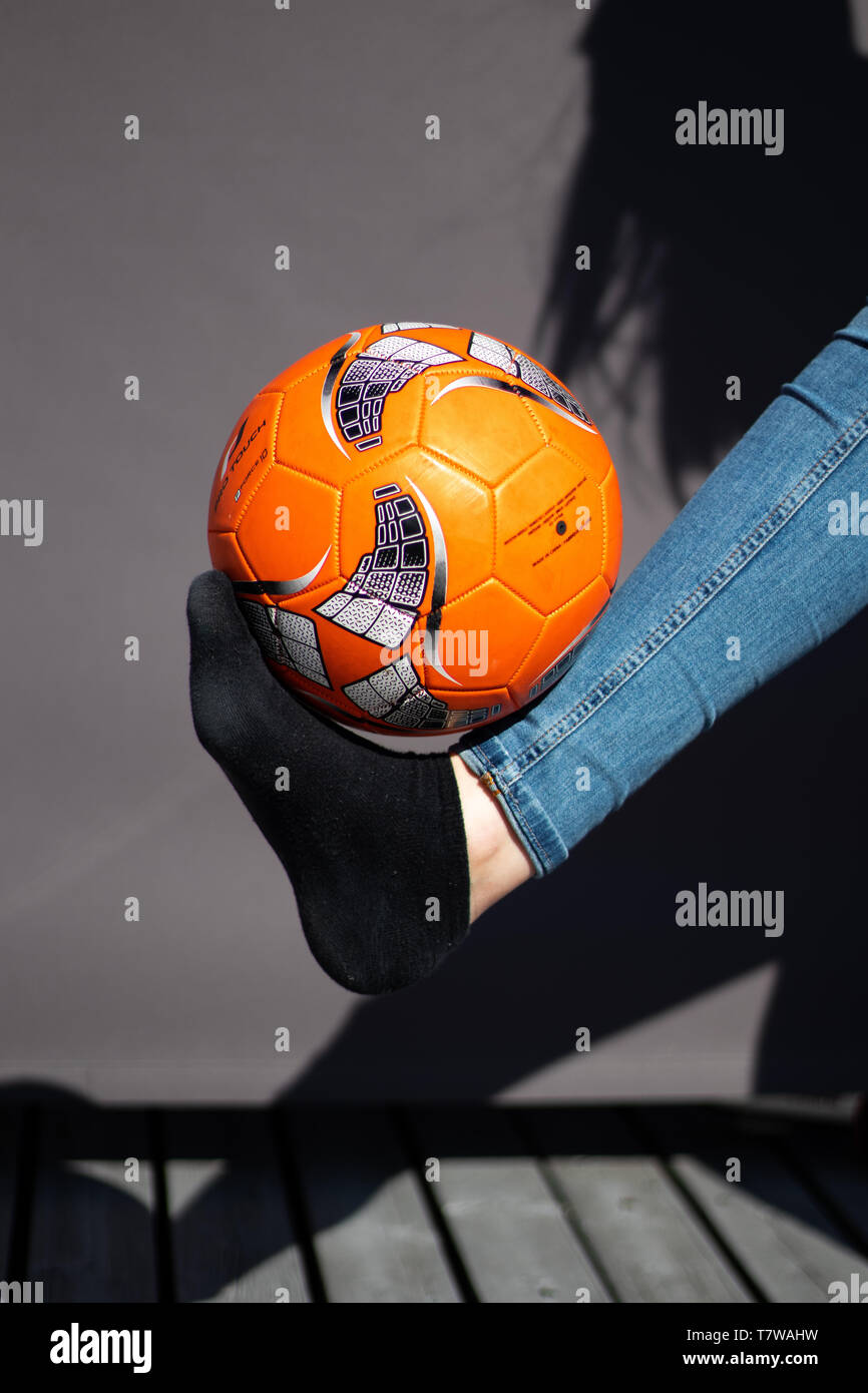 Balancing an orange soccer ball on foot Stock Photo - Alamy