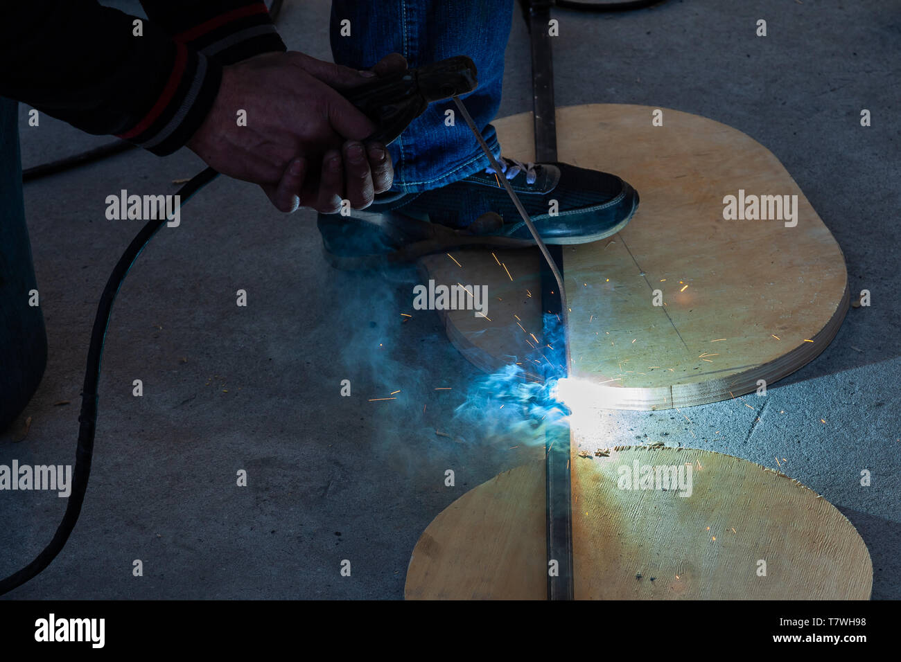 Close-up view strong man is a welder in blue working overalls without ...