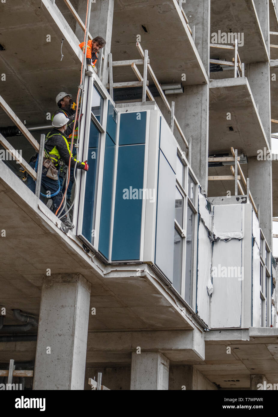 Three construction workers are preparing to fix the exterior panels on ...