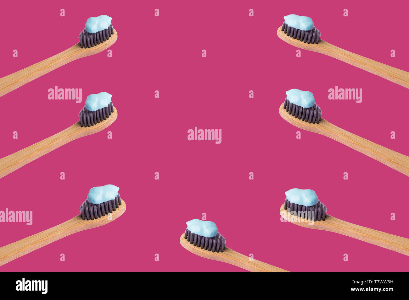 Frame of bamboo toothbrushes with blue toothpaste isolated on pink ...