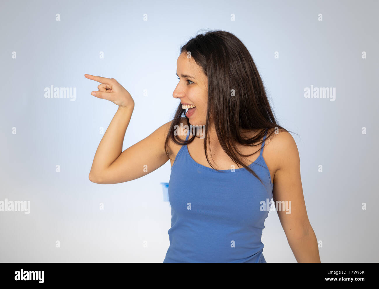Beautiful Latin Young Woman Pointing Finger At Copy Space Looking