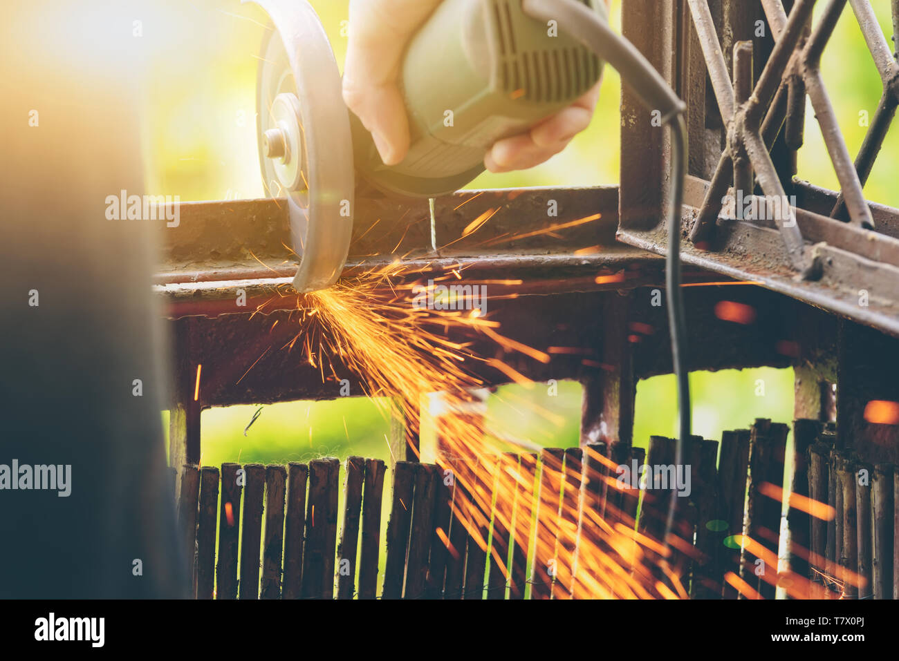 Man using angle grinder, cutting metal, a lot of flashing sparks are ...
