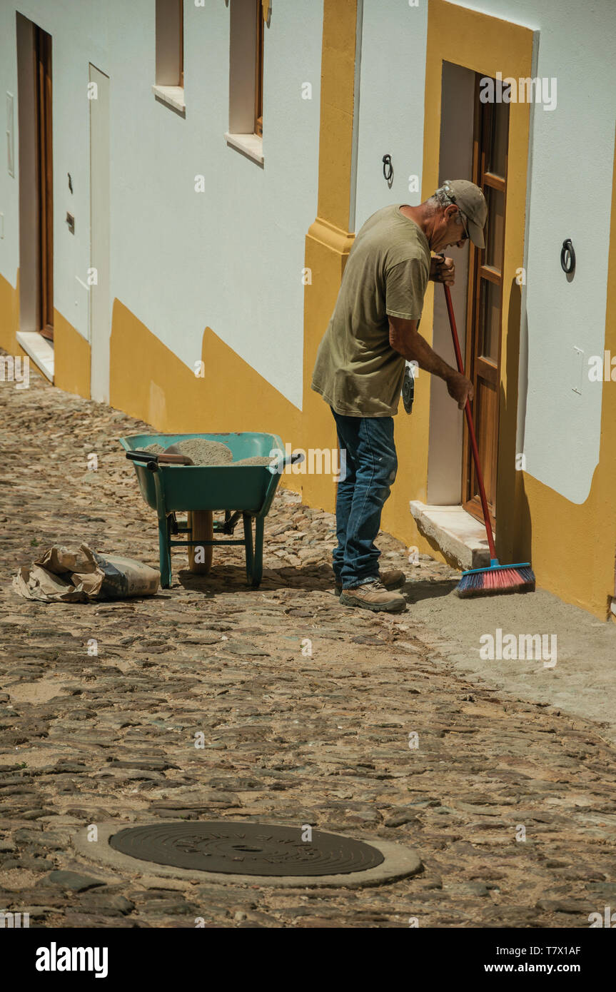 Man sweeping the front of colorful house at the main street of ...