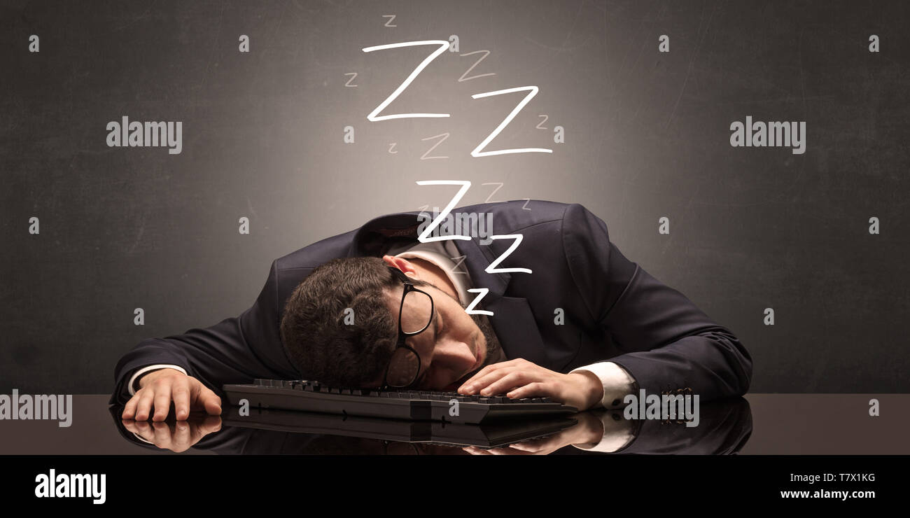 Young businessman fell asleep at the table on his keyboard concept ...