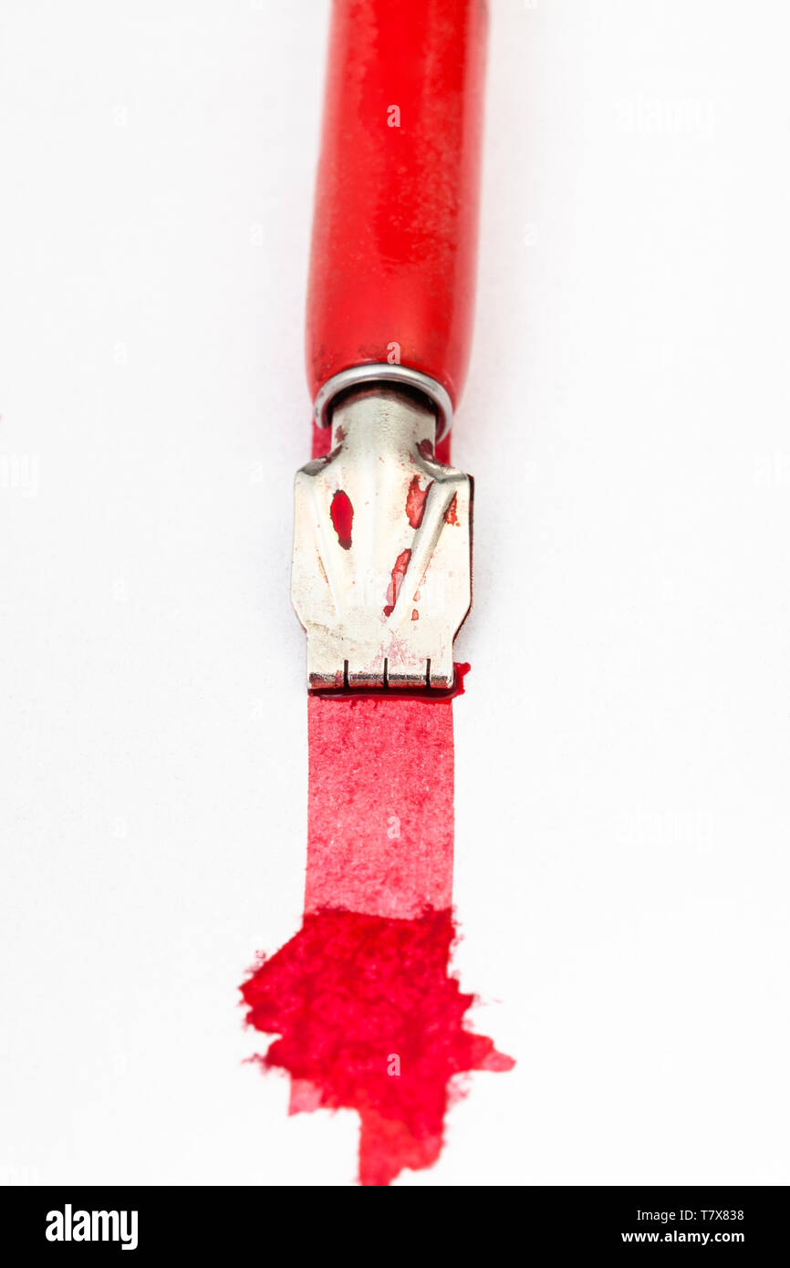red dip pen draws red line with blot on white paper by wide nib close ...