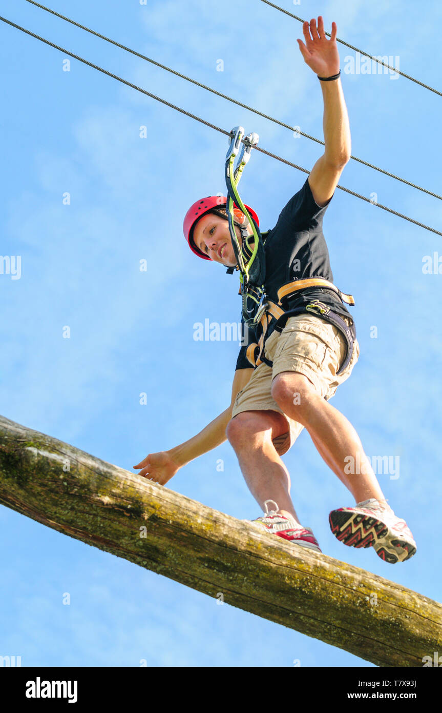 Young man has fun while absolving an balance exercise in high ropes ...