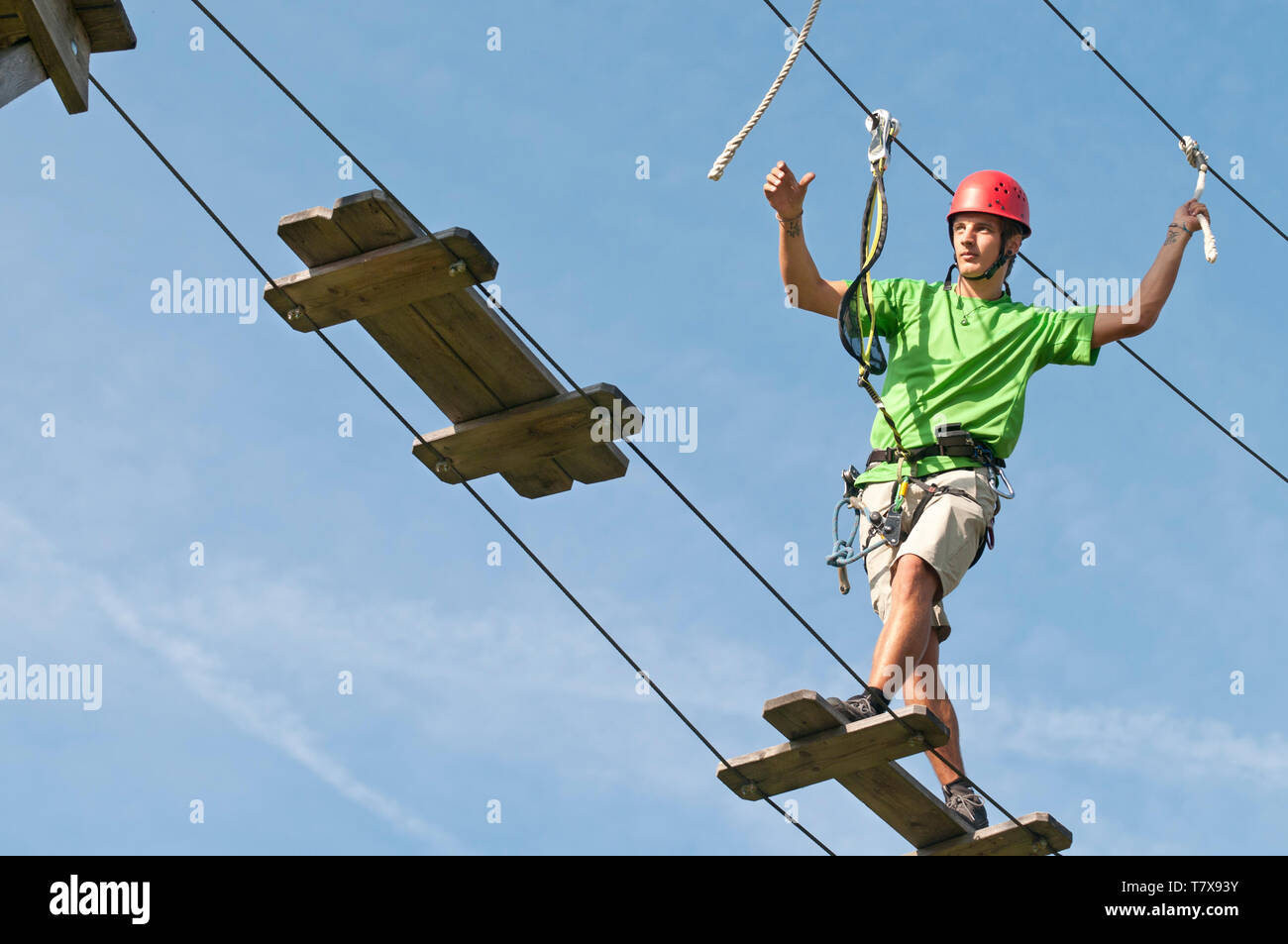Young man has fun while absolving an balance exercise in high ropes ...