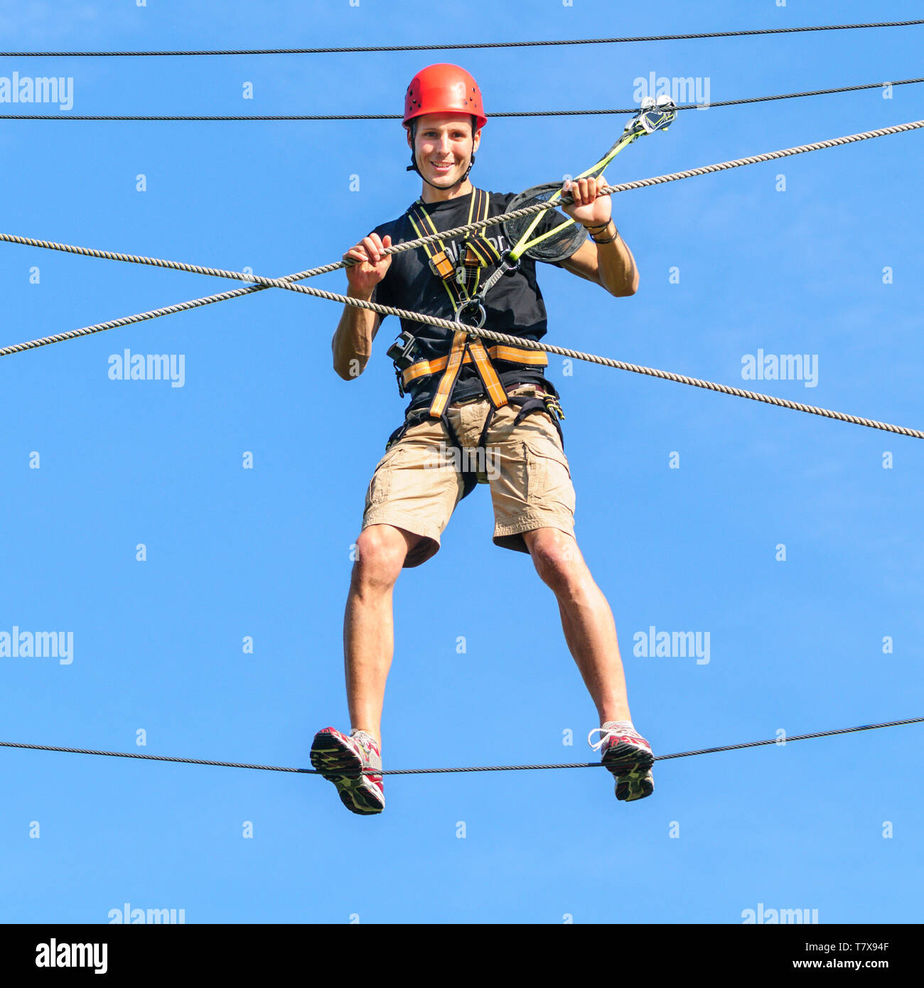 Young man has fun while absolving an balance exercise in high ropes ...