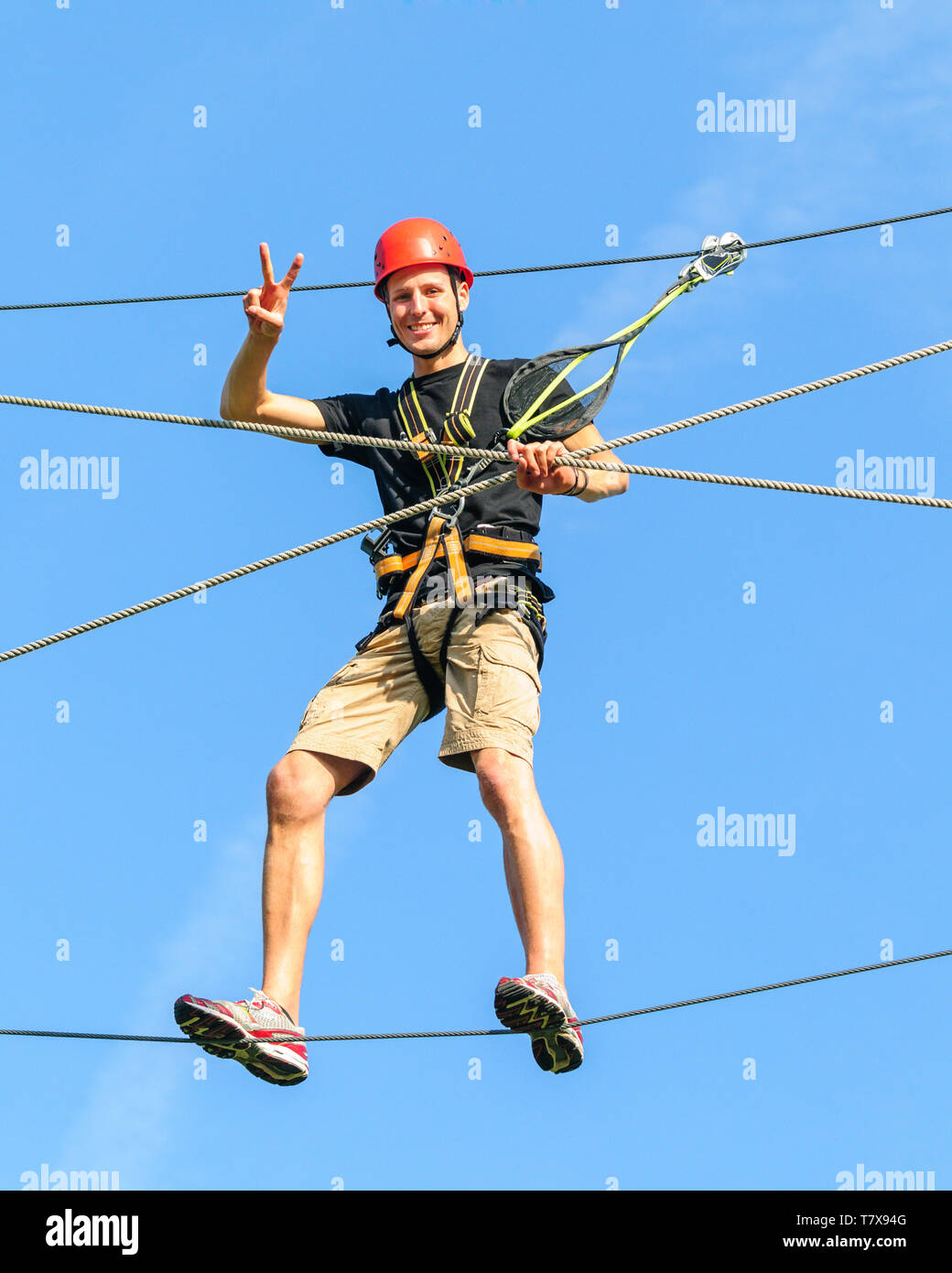 Young man has fun while absolving an balance exercise in high ropes ...