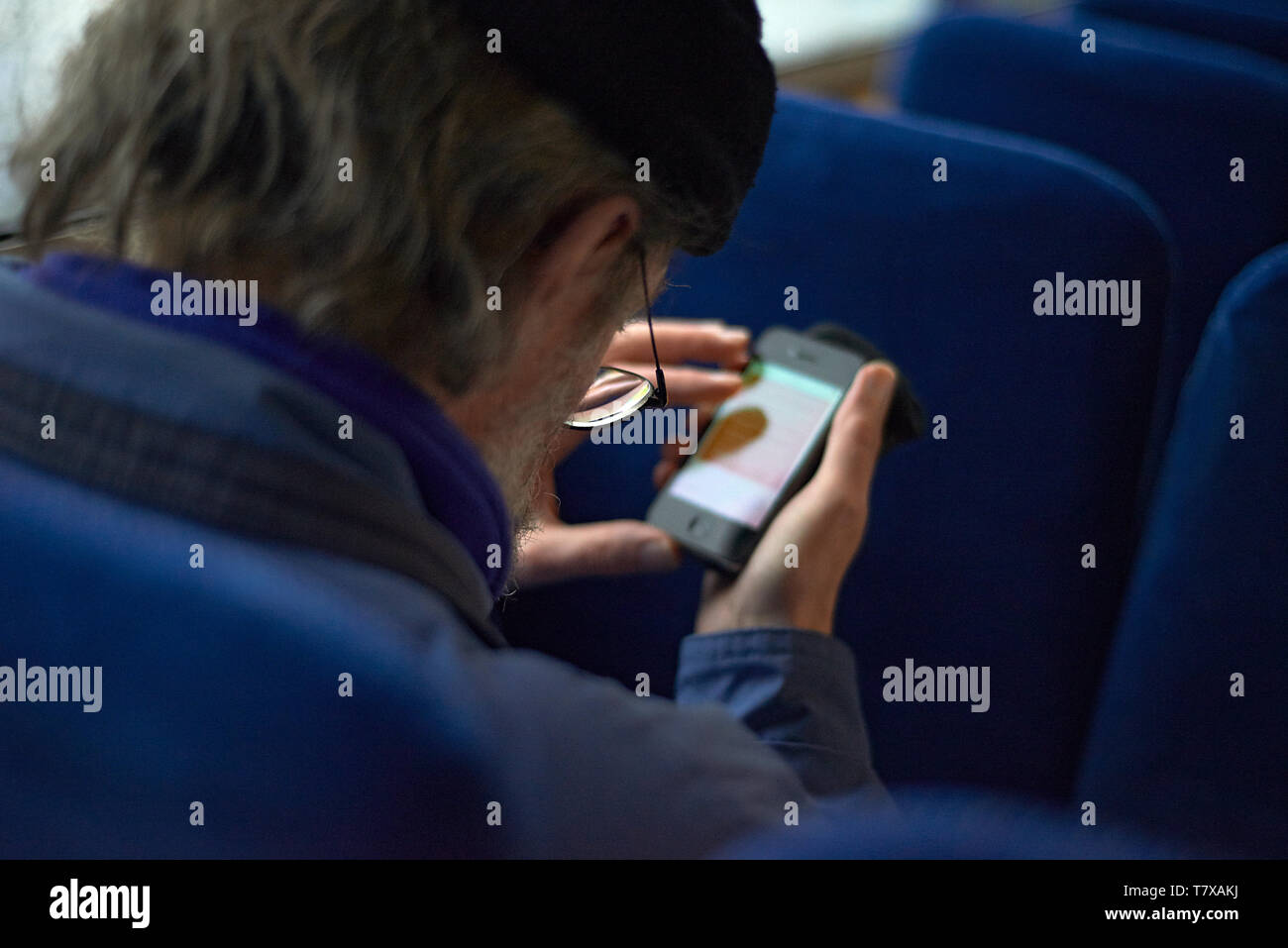 Over the shoulder shot of an elderly man looking at his mobile phone ...
