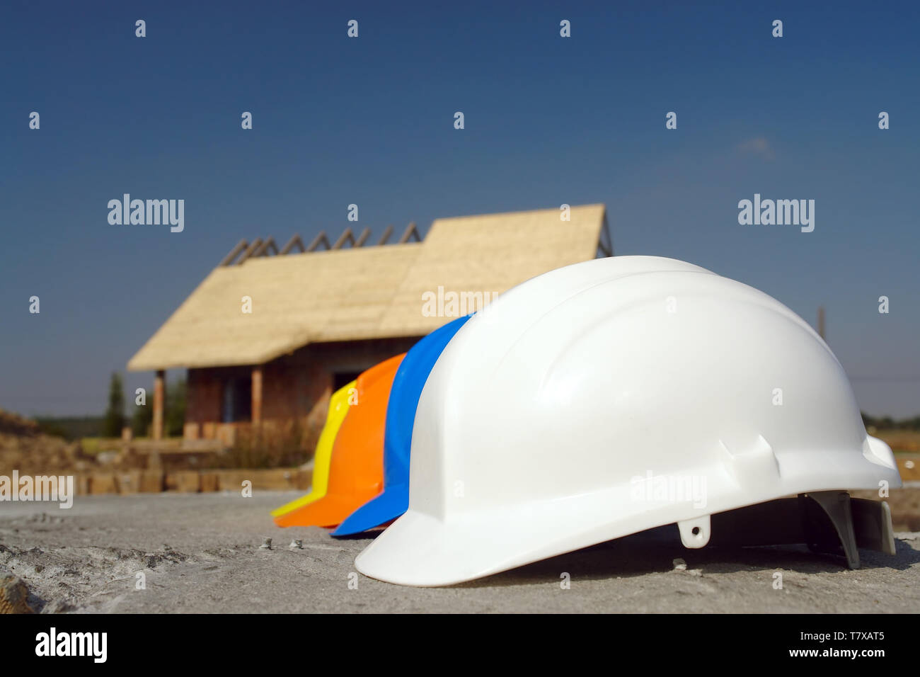 Row of four hard hats in white, blue, orange and yellow colors with ...