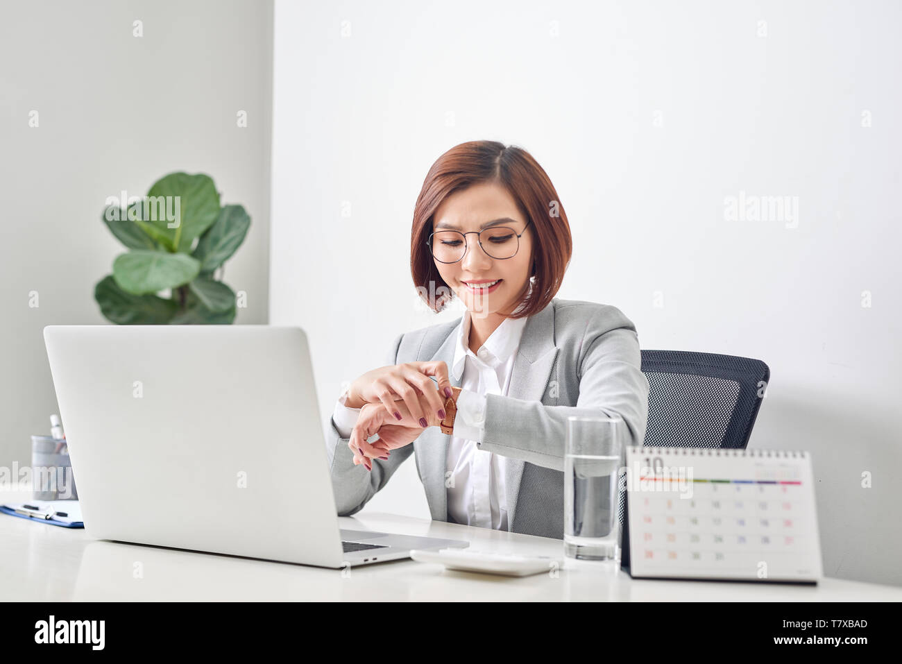 Young businesswoman checking time on her wristwatch at workplace. Time ...