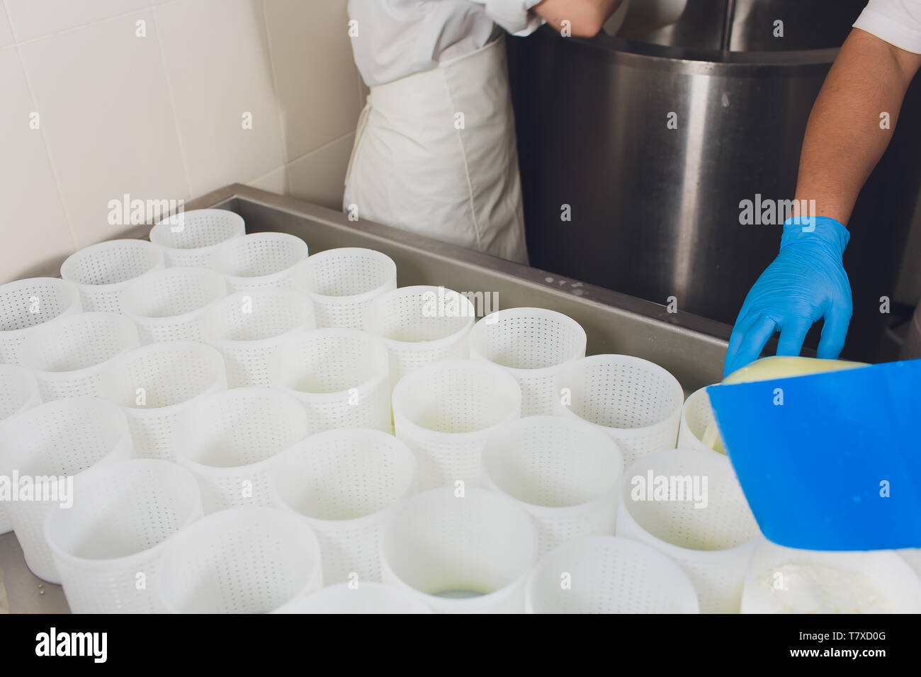 Close-up of a man forming cheese into the plastic molds at the small ...