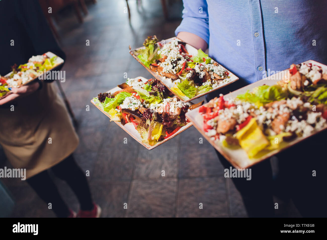 Two meat plate with salad leaves and summer salad in waiter's hand ...