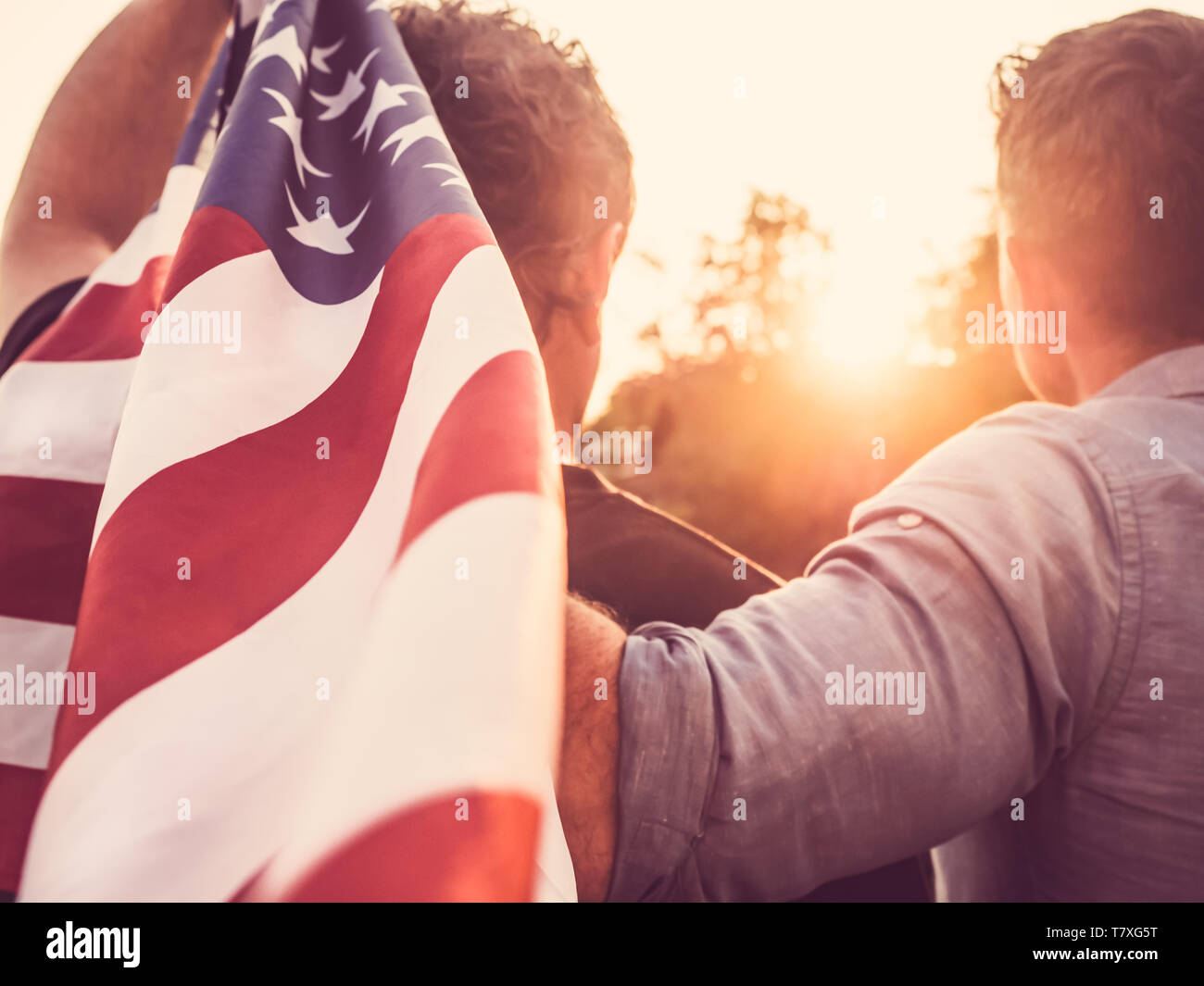 Two friends hold American Flag at sunset Stock Photo - Alamy