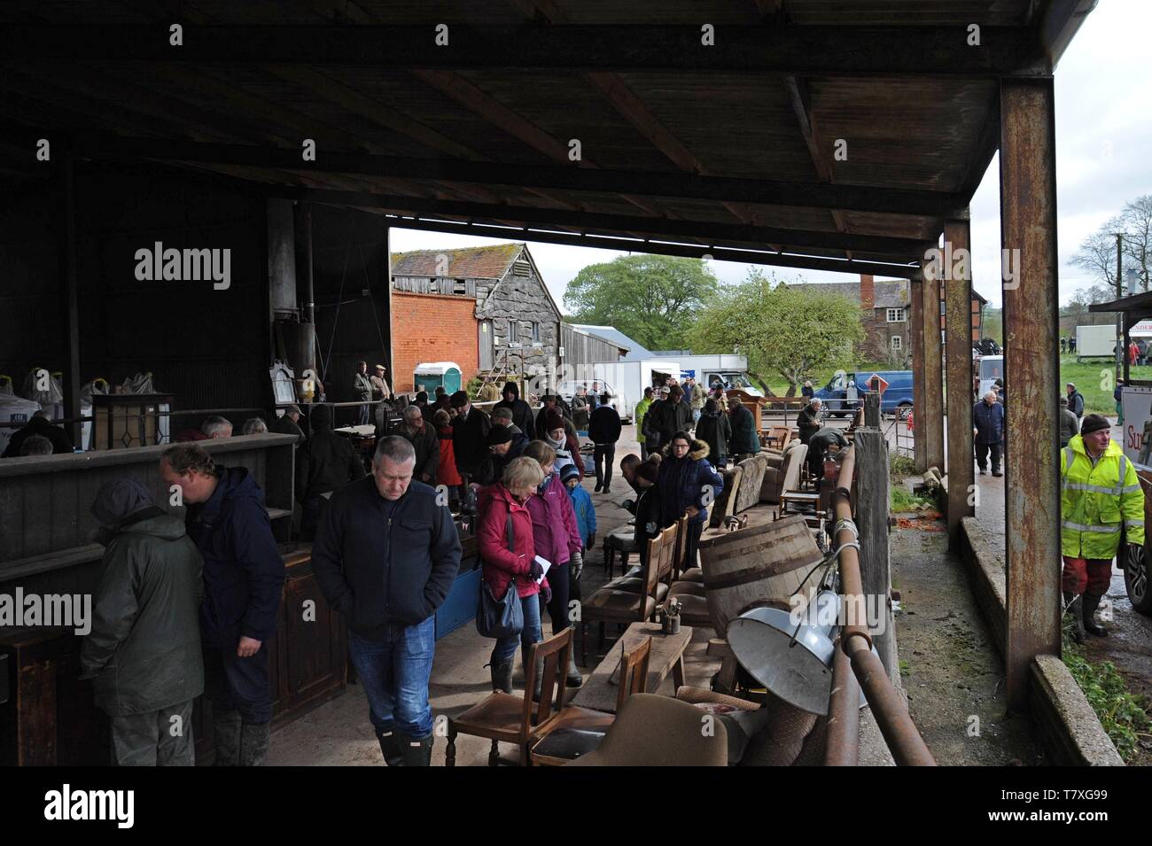People examining old furniture and vintage farm items at a farm sale of ...