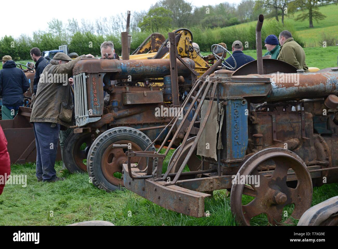 People examining tractors and vintage farm machinery on sale at a farm ...