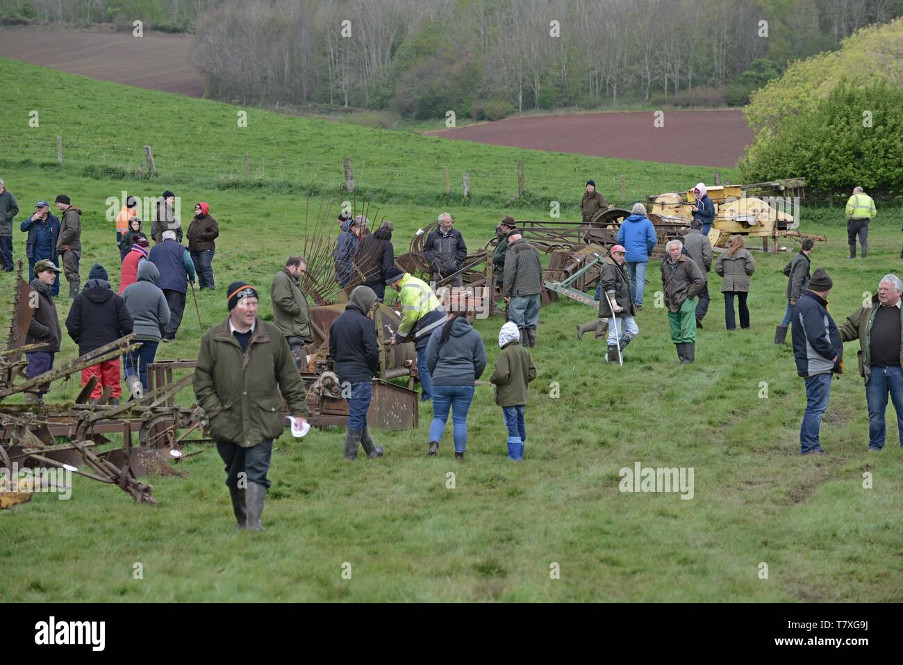 People examining tractors and vintage farm machinery on sale at a farm ...