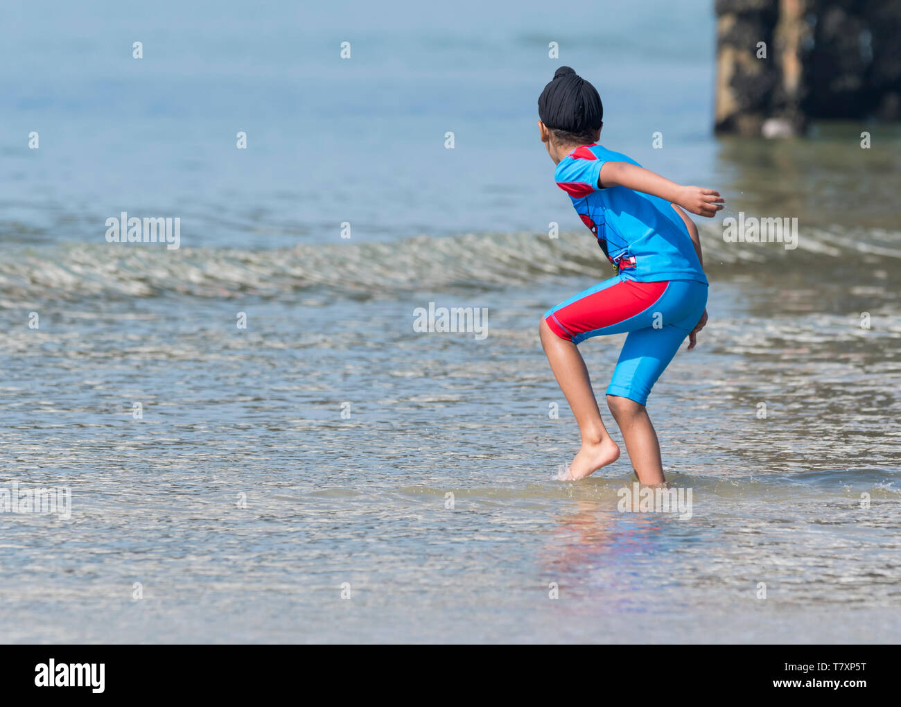 Young boy wearing a turban paddling in the sea in Spring in Brighton ...