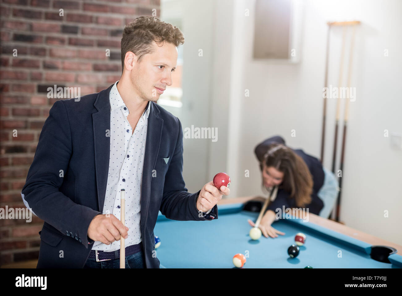Portrait of handsome billiard player holding a ball and fashionable ...
