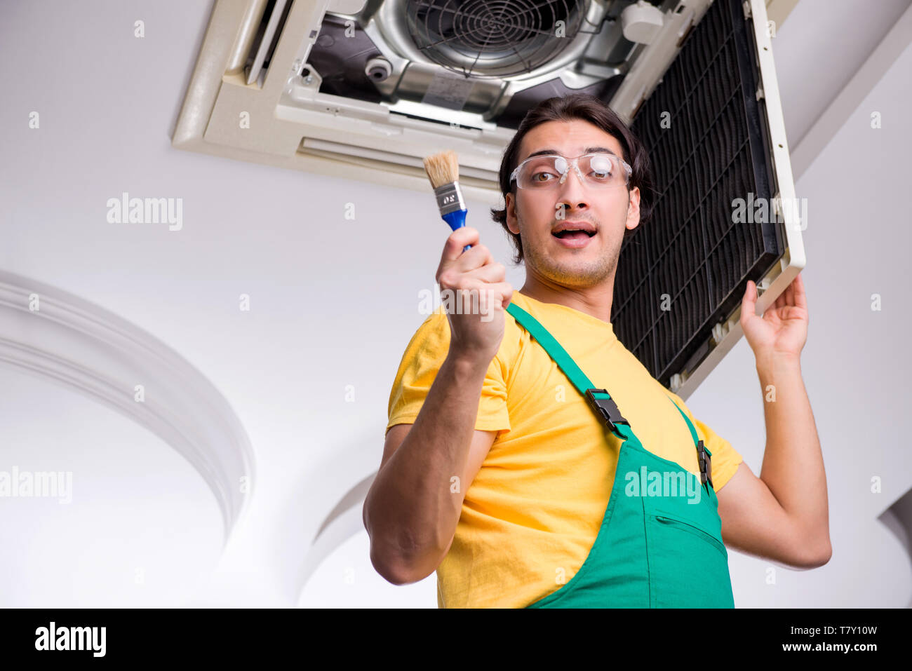 Young repairman repairing ceiling air conditioning unit Stock Photo - Alamy