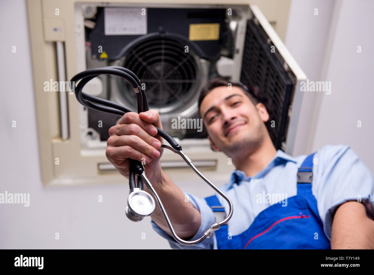 Young repairman repairing ceiling air conditioning unit Stock Photo - Alamy