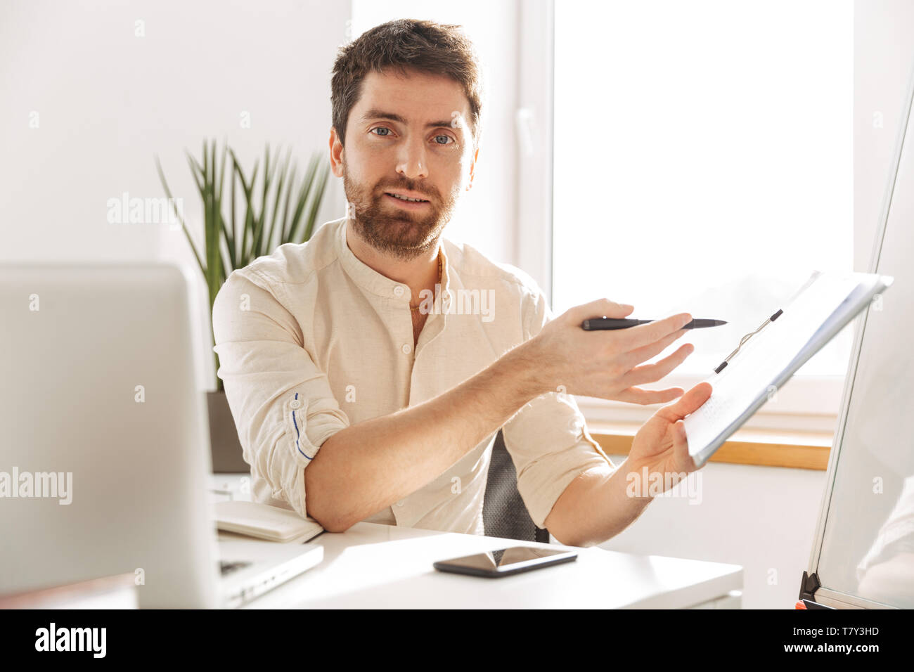 Image of successful office guy 30s wearing white shirt using laptop and ...