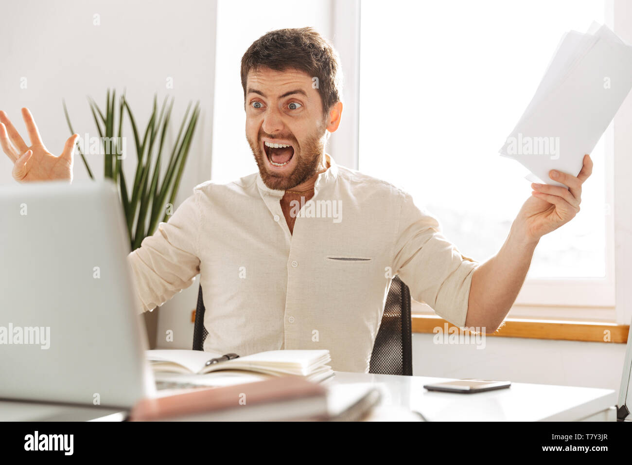 Image of aggressive office worker 30s wearing white shirt using laptop ...