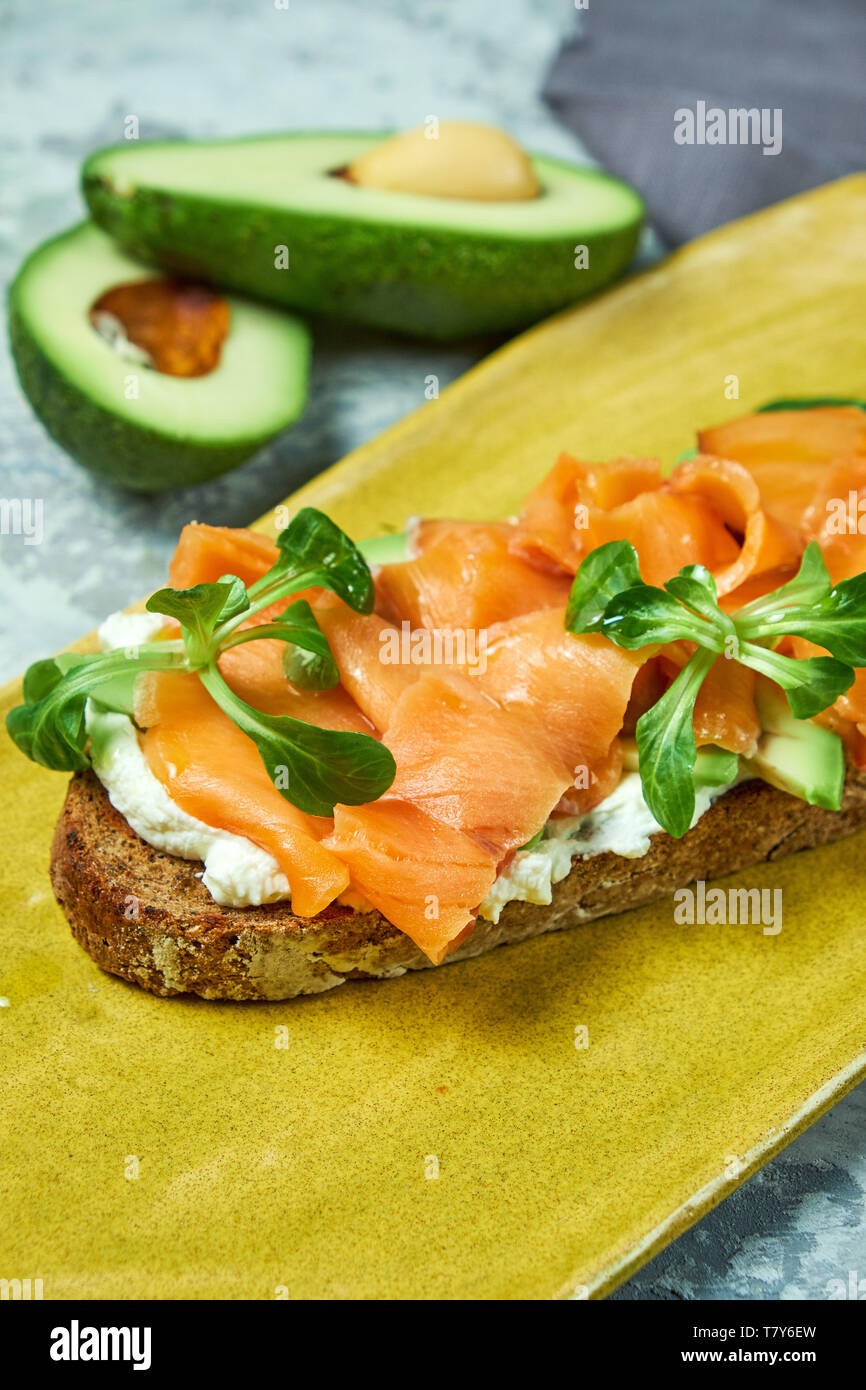 On a yellow plate of bruschet with salmon, next to it is a slice of ...