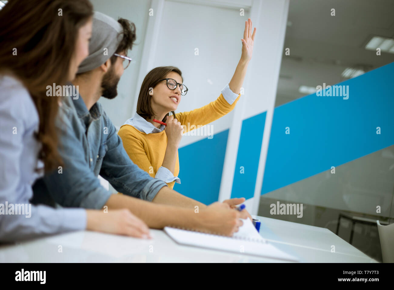 Group of young students rising hands to answer the question during the ...