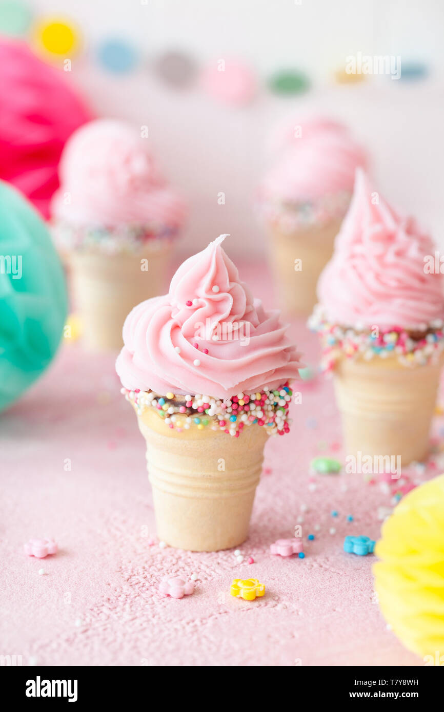 Pink soft serve ice cream with colorful sprinkles in little waffle cups ...