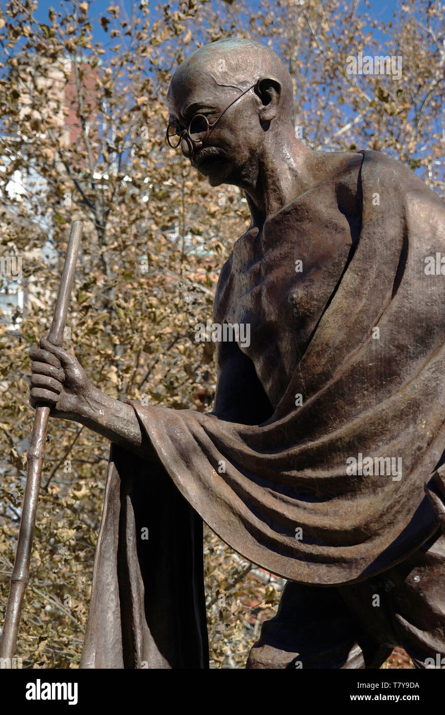 A closed up view of the bronze statue of Mahatma Gandhi in front of ...