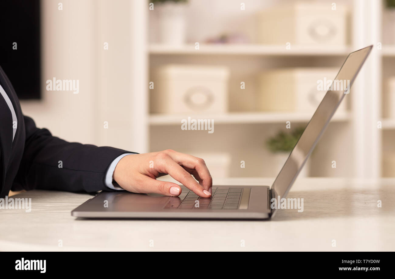 Business woman below chest working on her laptop in a cozy environment ...