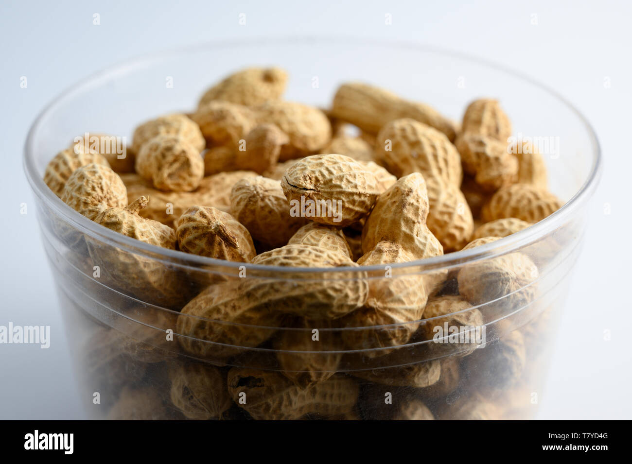 Plastic cup full of peanuts in nutshell on white background Stock Photo ...