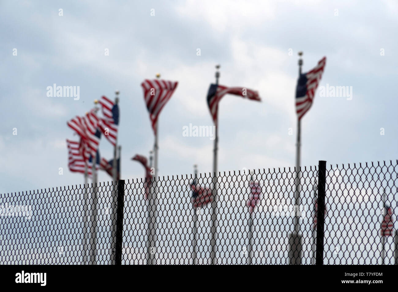 Waving usa flags behind metallic fence grid Stock Photo - Alamy
