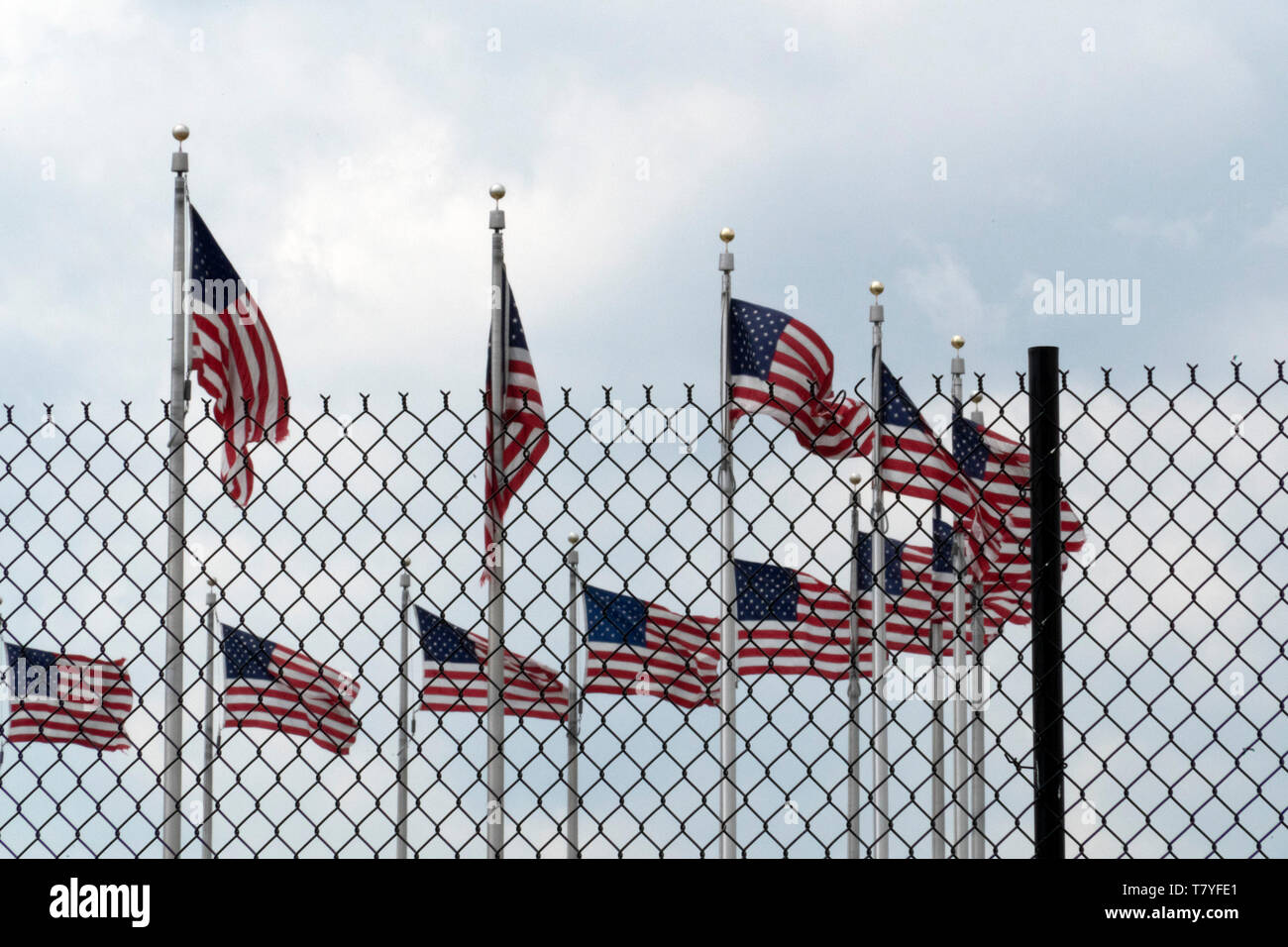Waving usa flags behind metallic fence grid Stock Photo - Alamy