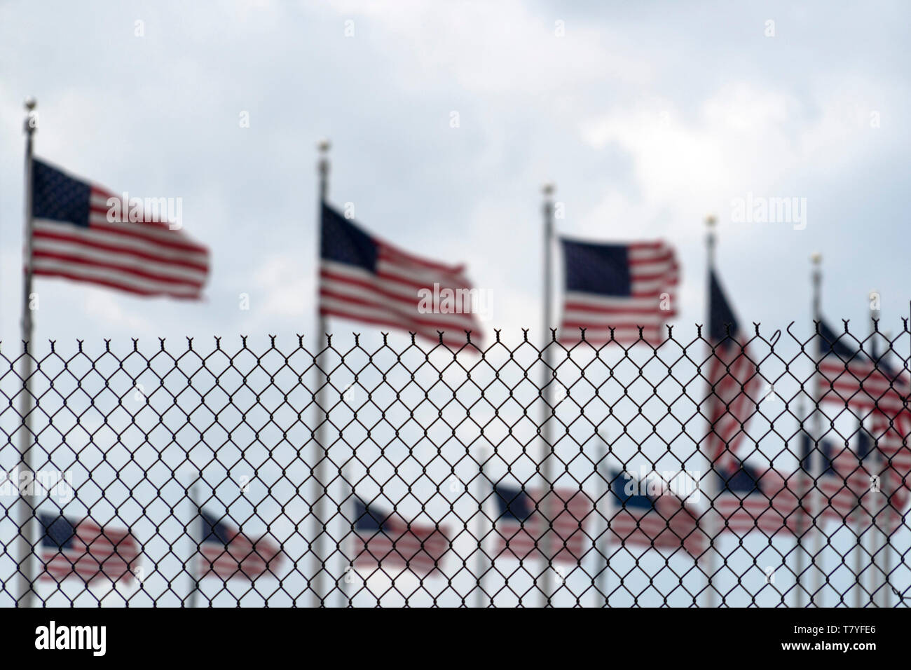 Waving usa flags behind metallic fence grid Stock Photo - Alamy